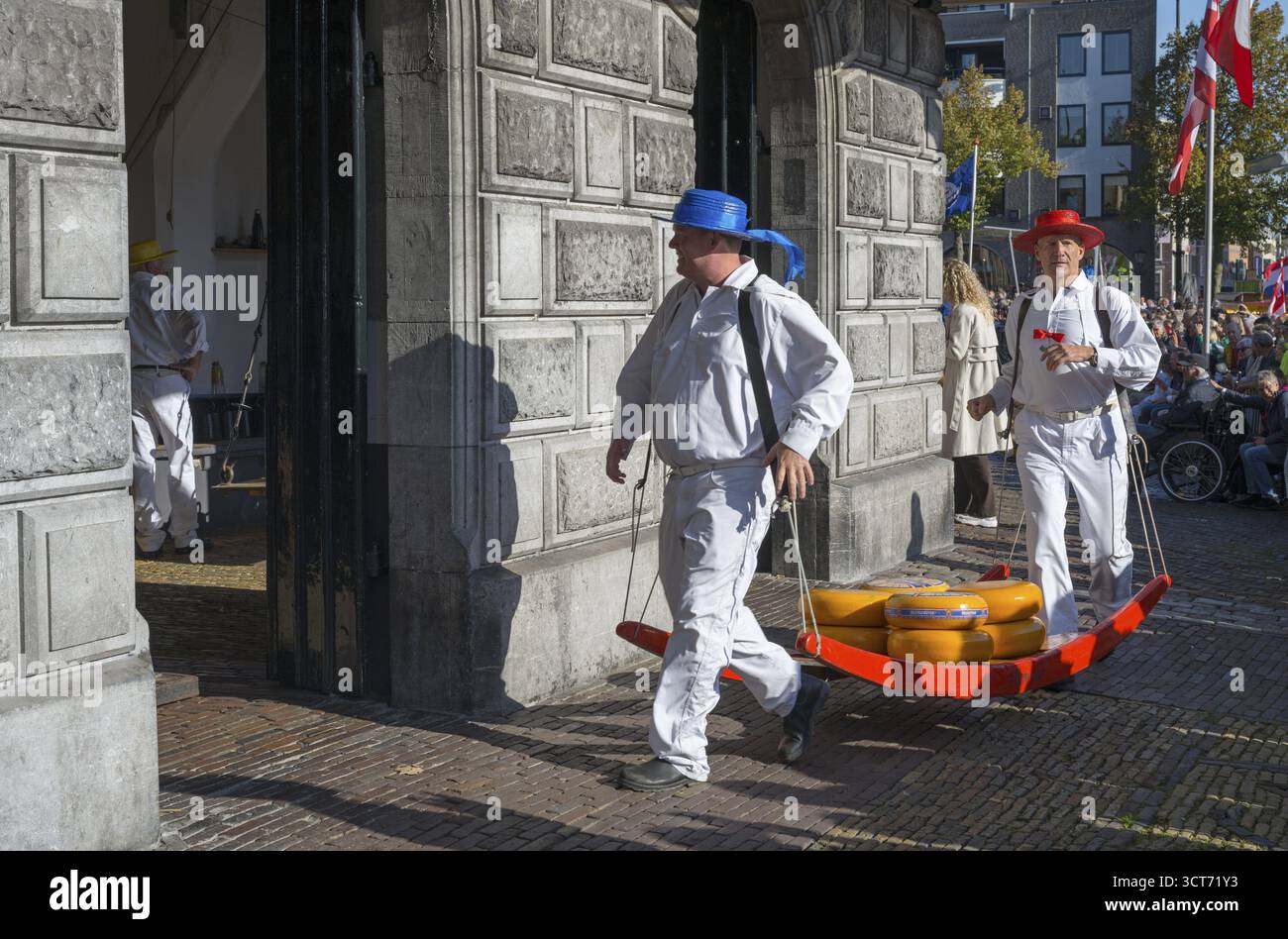 Men in traditional clothing transporting cheese at a historic building ...