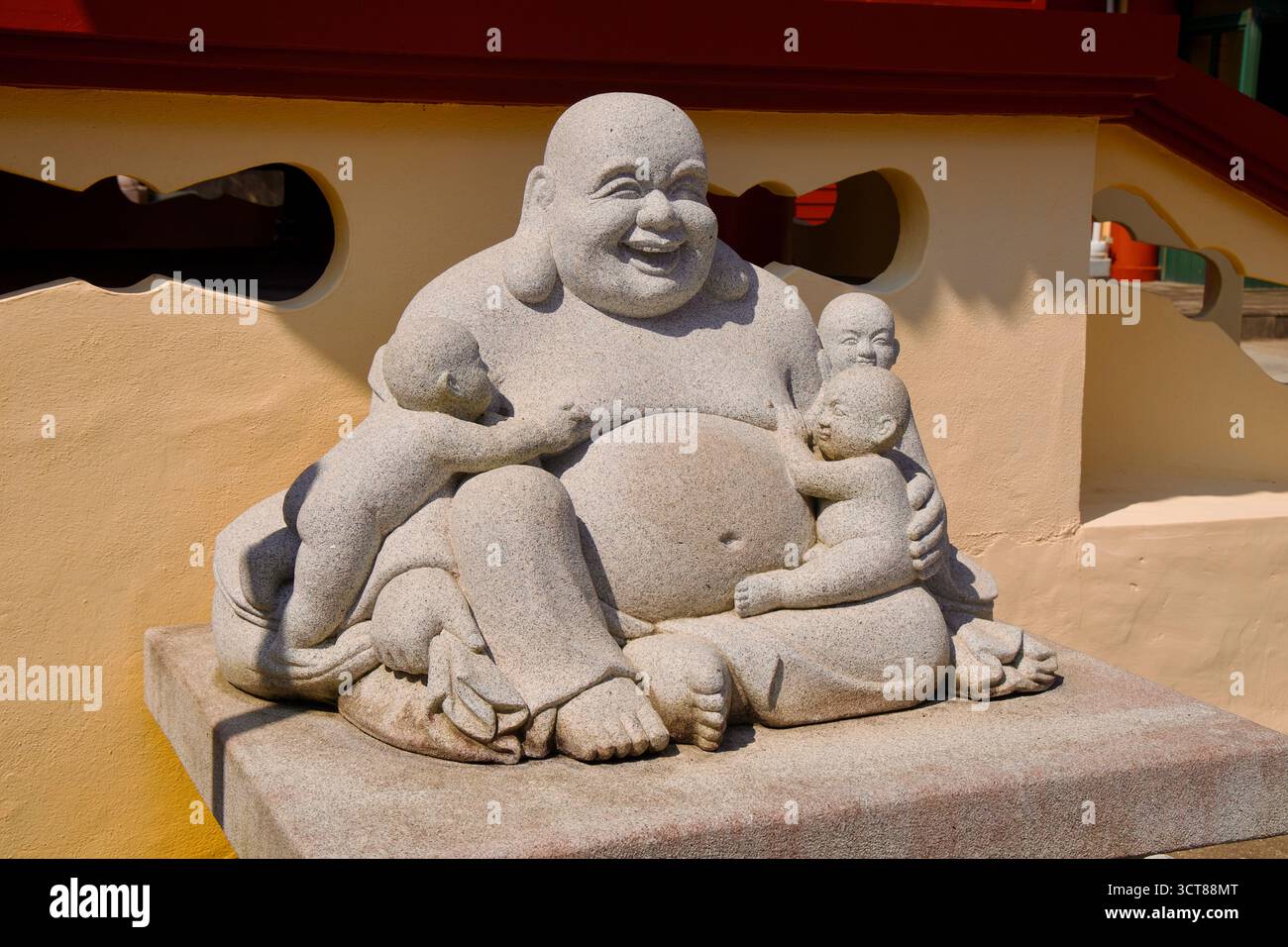 A granite statue of the Laughing Buddha surrounded by playful children ...