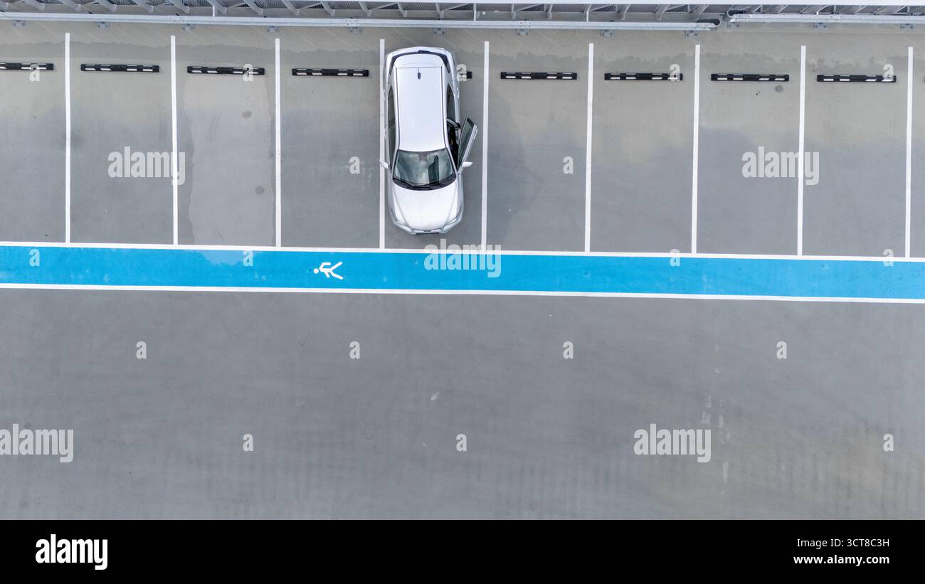 Aerial view of a single car parked in an empty parking lot with marked ...