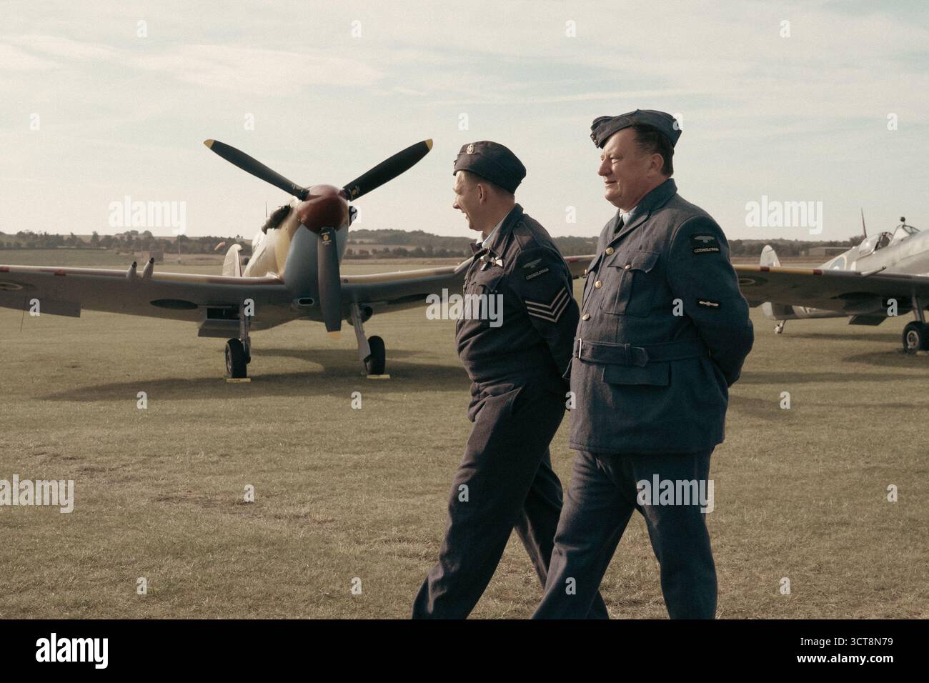 Two RAF personnel in period uniform walking past Spitfire at Duxford ...