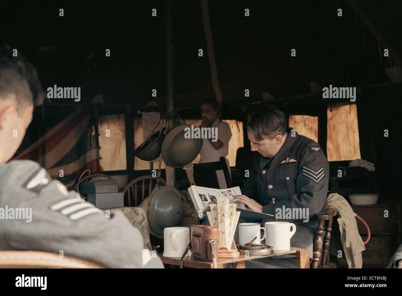RAF servicemen in wartime barracks reading newspaper at Duxford Stock ...