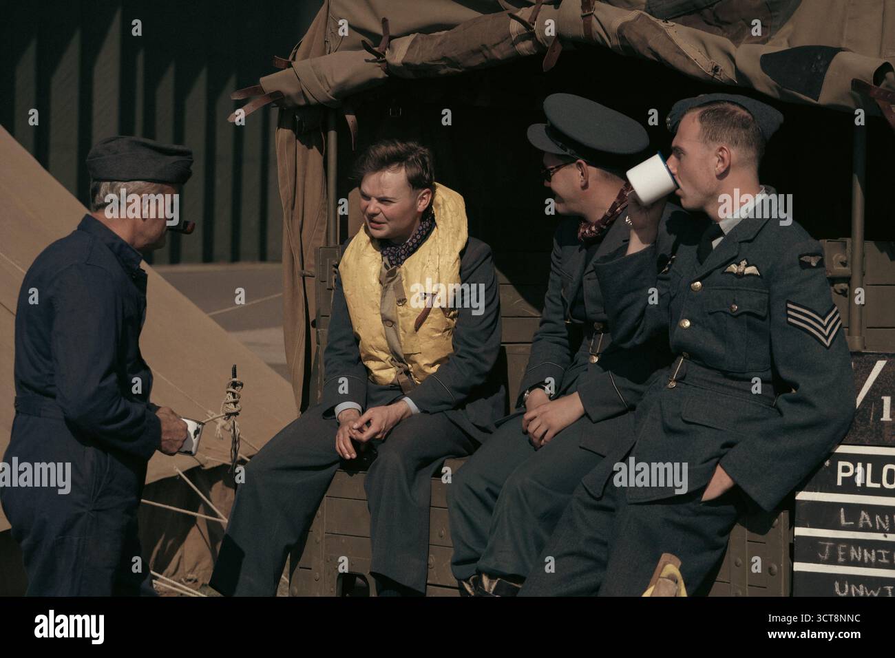 RAF aircrew in period uniforms discussing mission beside vintage ...