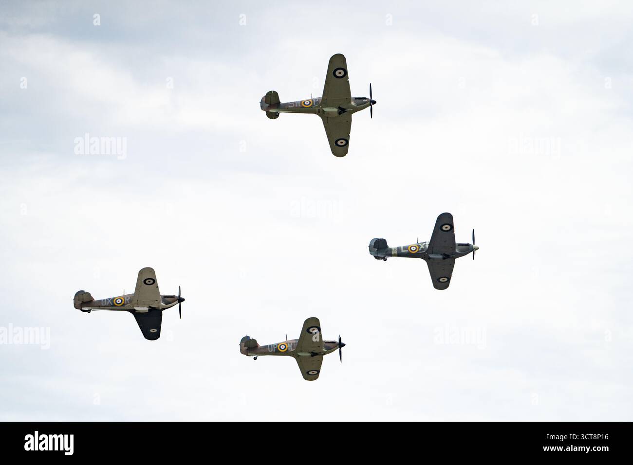 Four RAF Spitfire fighters flying in formation against cloudy sky at ...