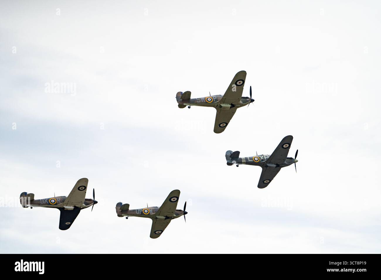 Four RAF Spitfire fighter aircraft in formation flight against cloudy ...