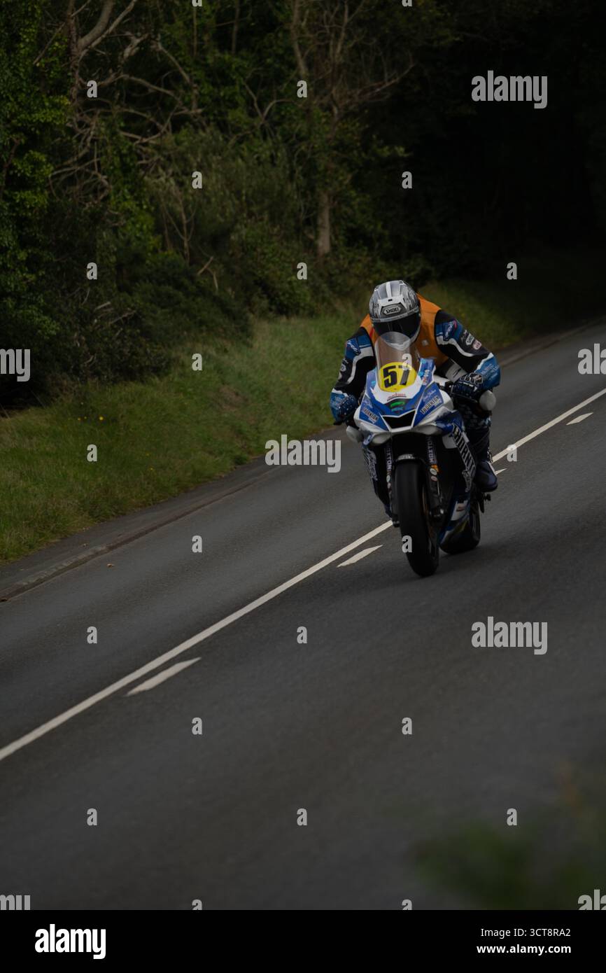 Racing motorcyclist on country road at Isle of Man TT with number 57 ...