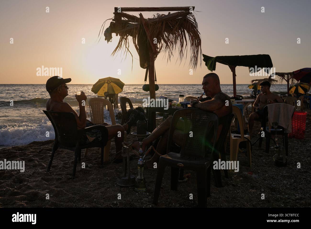 People enjoy the sunset at a public beach on the Mediterranean sea, in ...