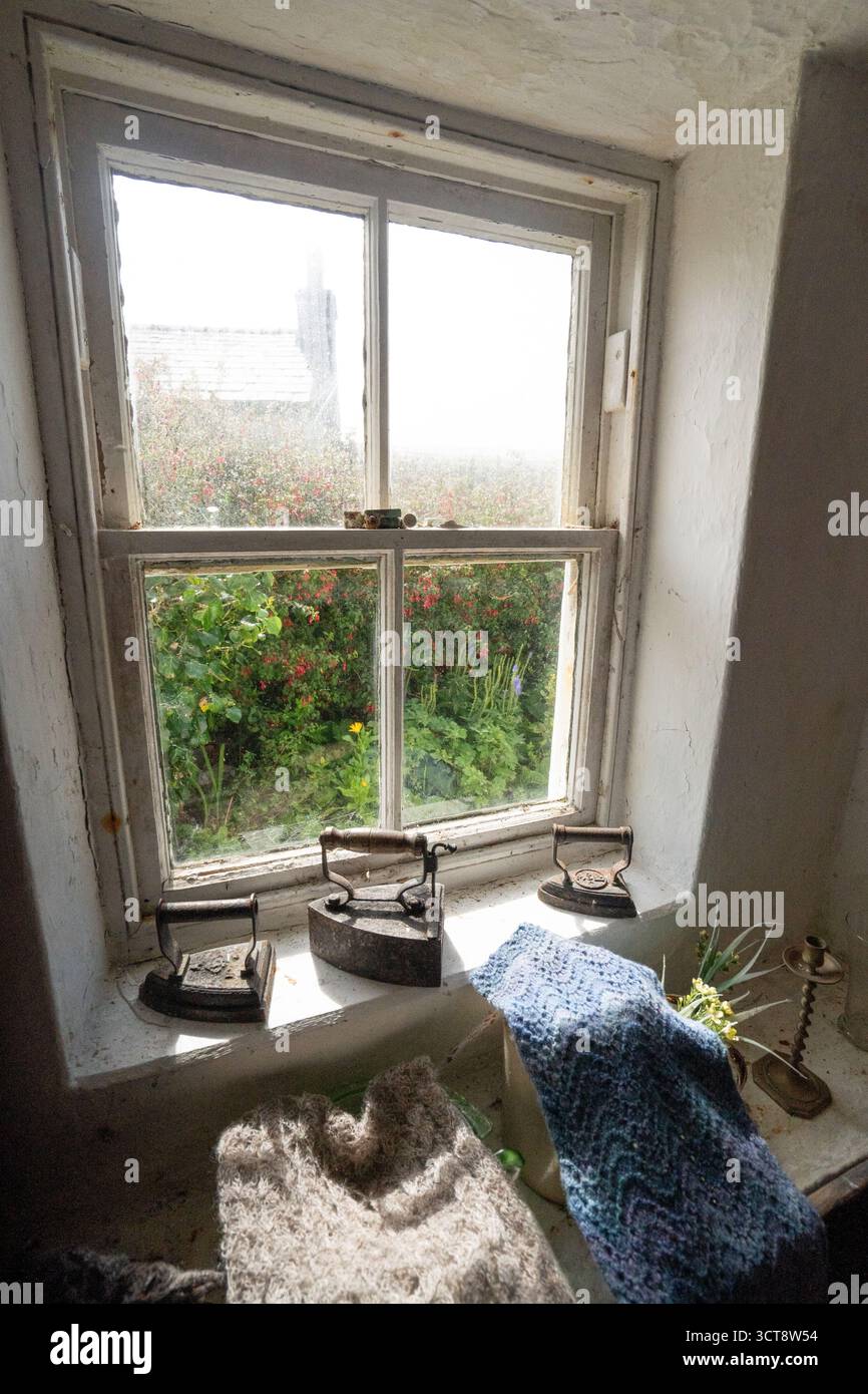 Traditional cottage window sill with vintage irons and garden view on ...