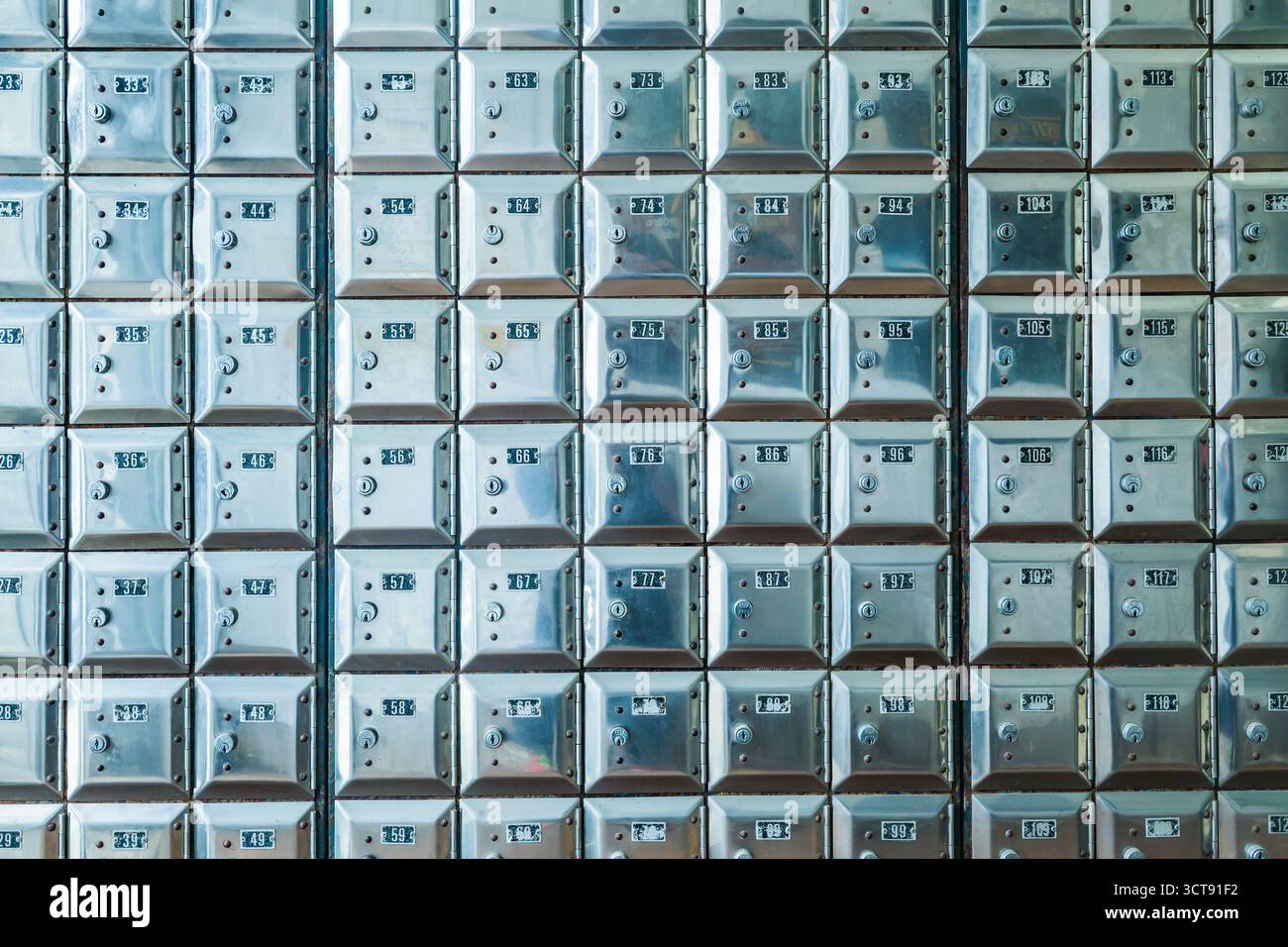 Wall full of rows of old shiny metal post office deposit value boxes ...