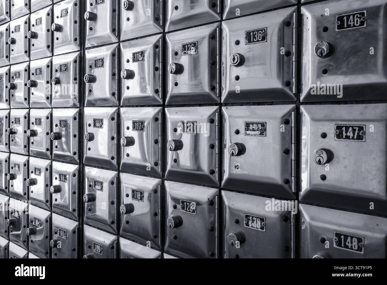 Wall full of rows of old shiny metal post office deposit value boxes ...