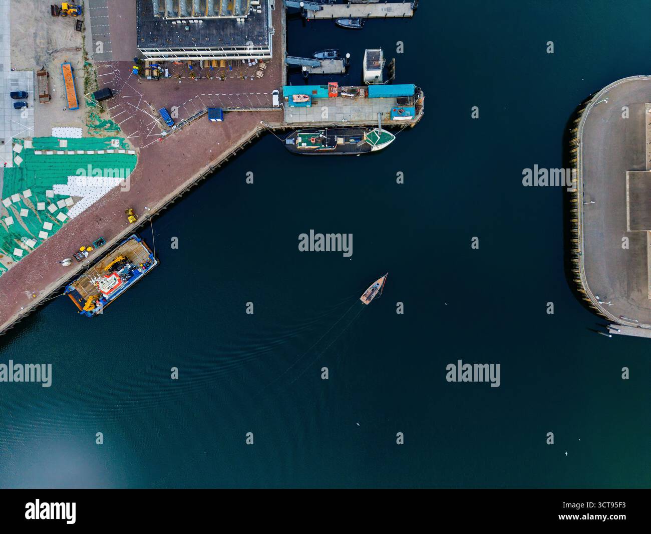 Aerial view of harbor with small boat leaving wake, moored vessels ...