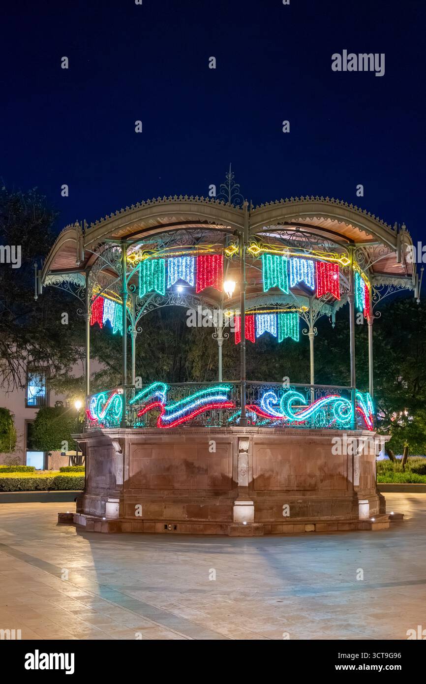 A colorful, illuminated gazebo with a red and green ribbon. The gazebo ...