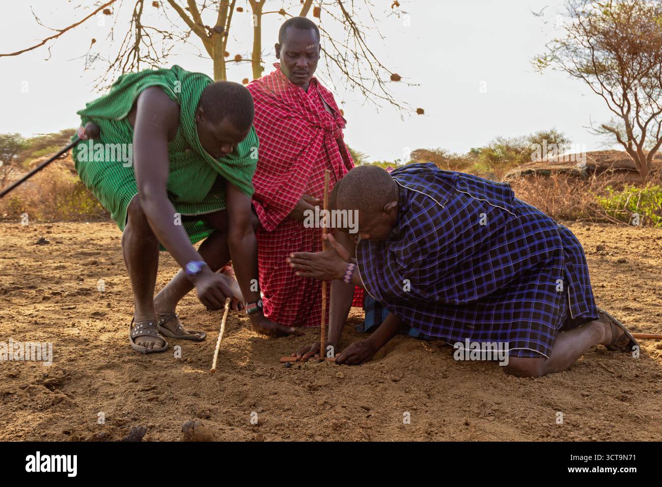 Maasai men in Kenya use sticks to start a fire, demonstrating ...