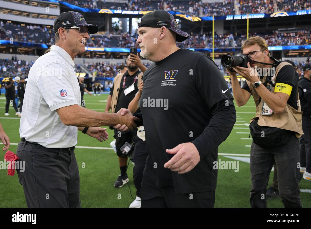 Los Angeles Chargers head coach Jim Harbaugh, left, shakes hands with ...