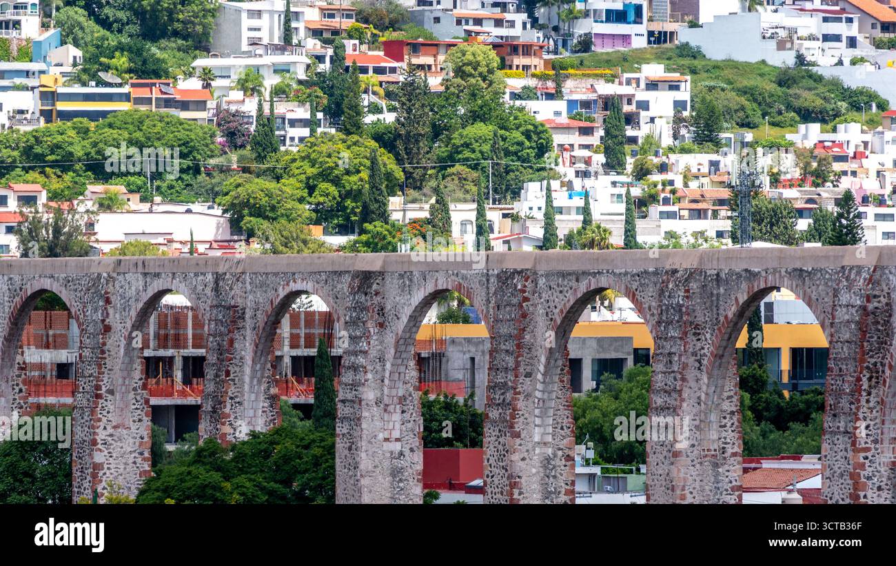A stone bridge spans a river in a city. The bridge is surrounded by ...