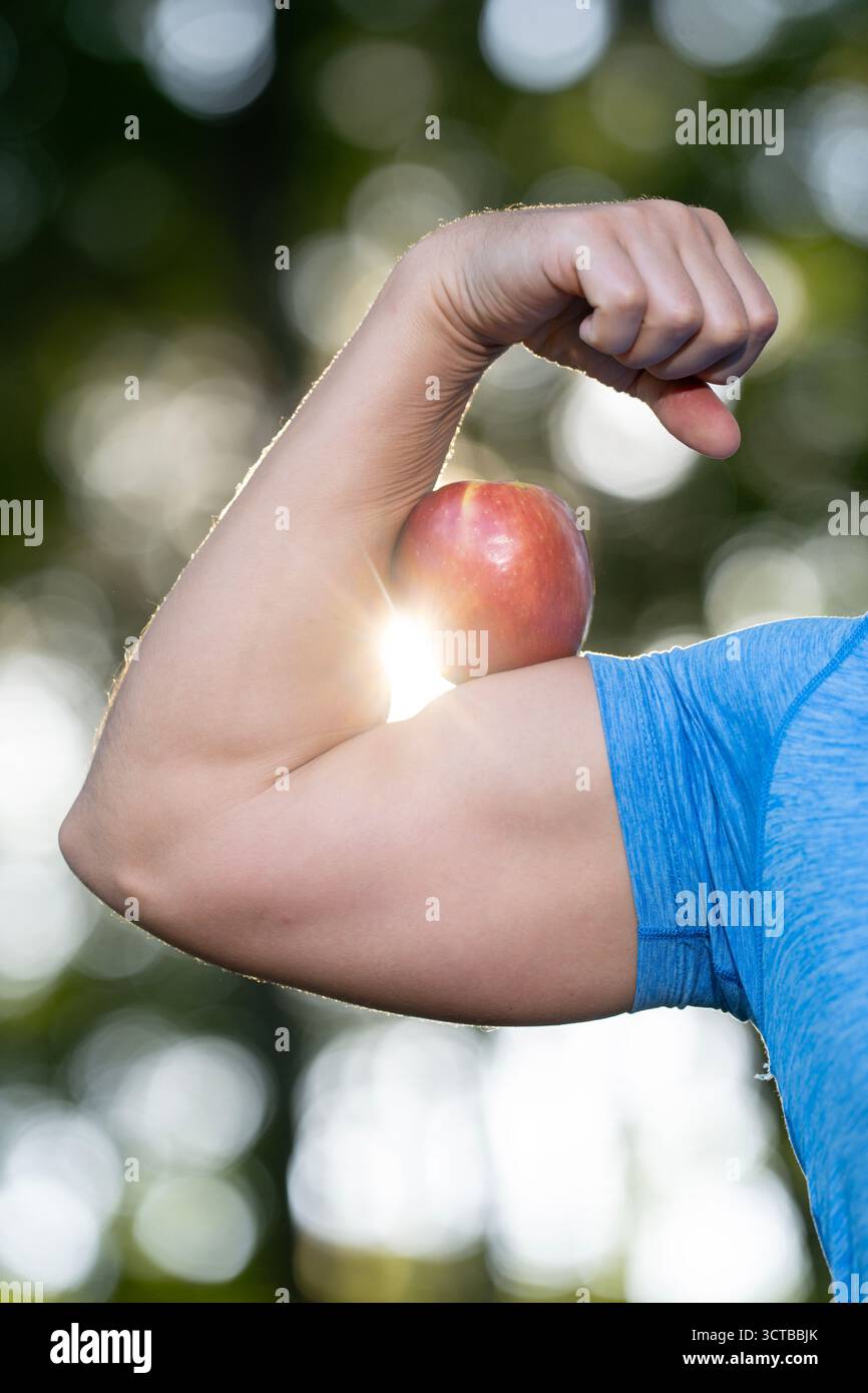 A strong man flexes his biceps while lifting dumbbells outdoors. Mature ...