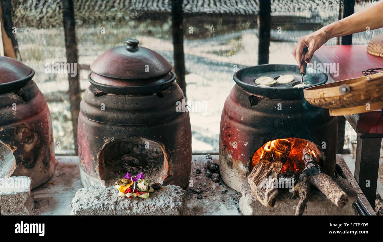 A Balinese woman cooking traditional "Laklak" cake using a clay stove ...