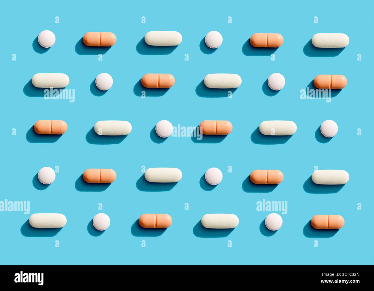 Pills and capsules arranged in a grid pattern on a bright blue ...