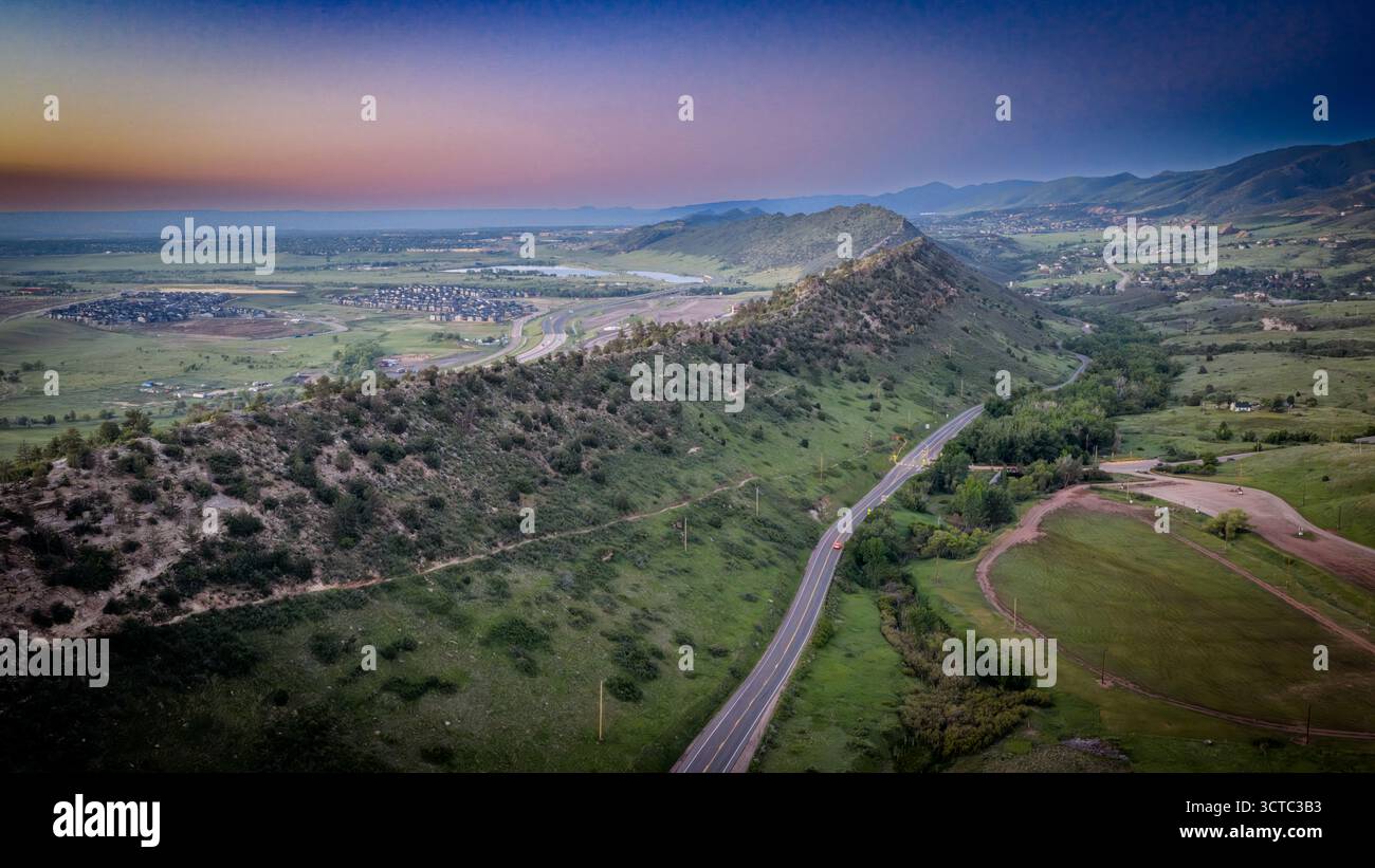 Aerial view of a lone highway cutting through lush green hills under a ...