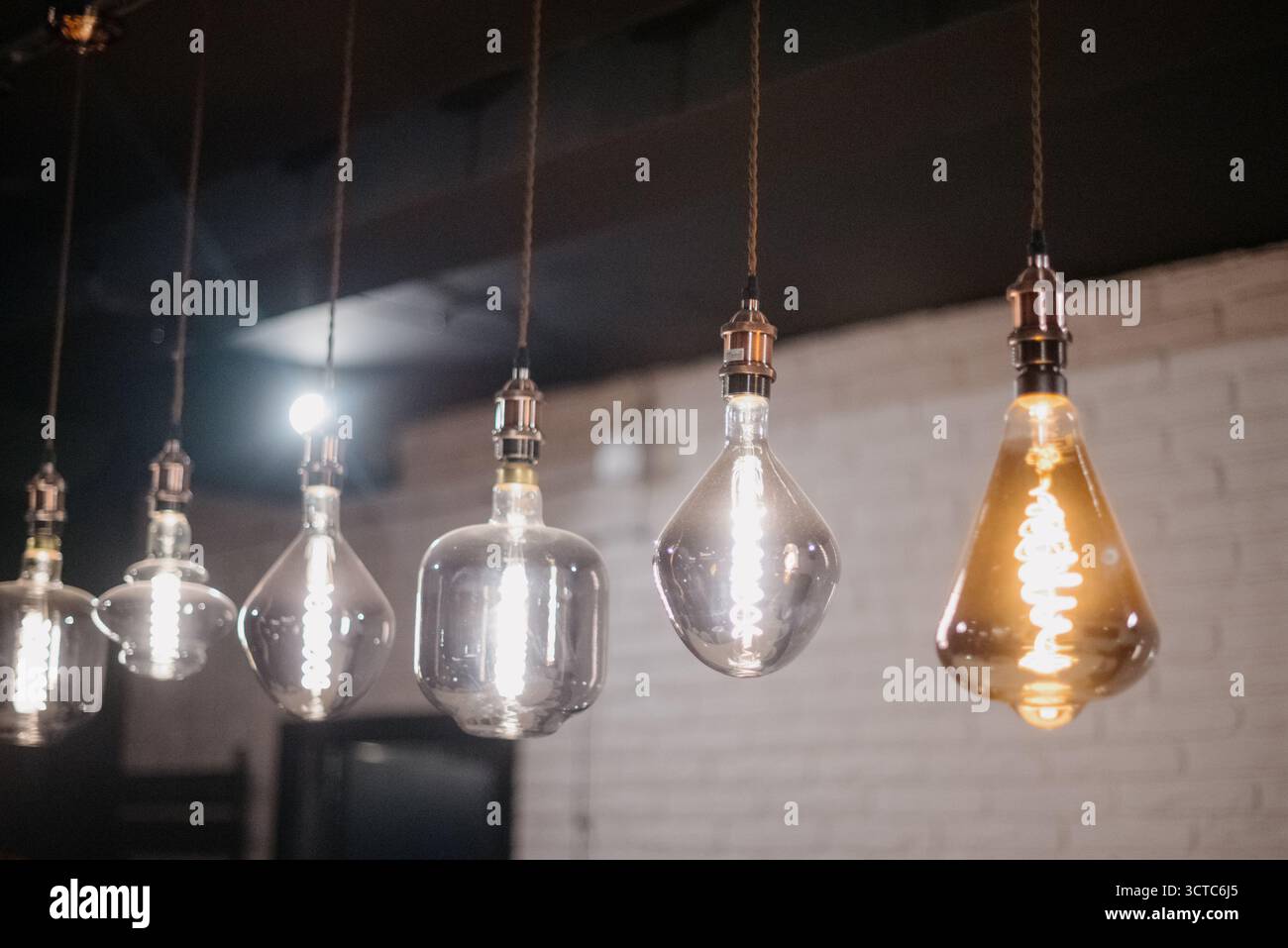 A row of vintage Edison pendant lamps in various shapes with warm and ...