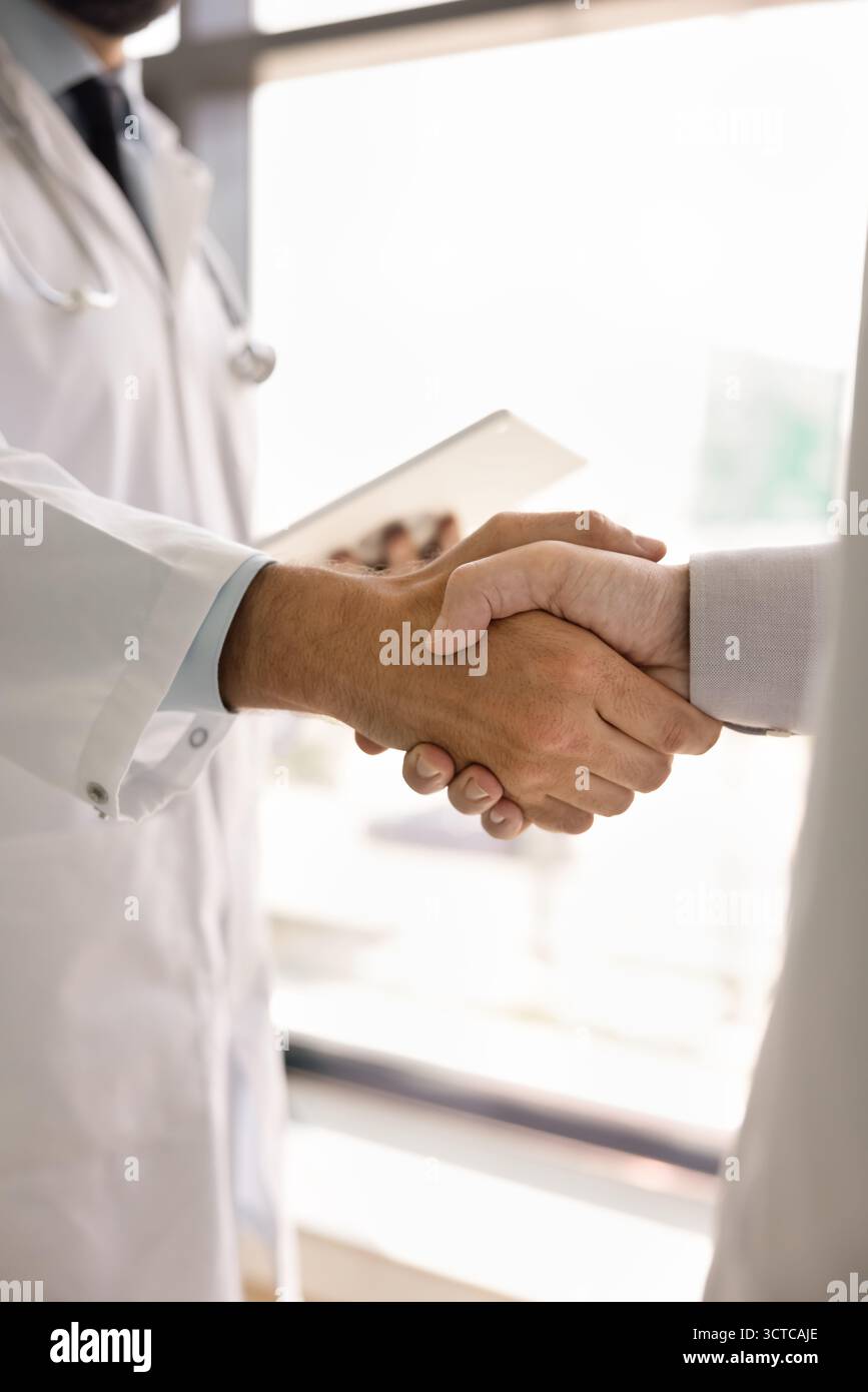 General practitioner greeting clinic patient with handshake gesture ...