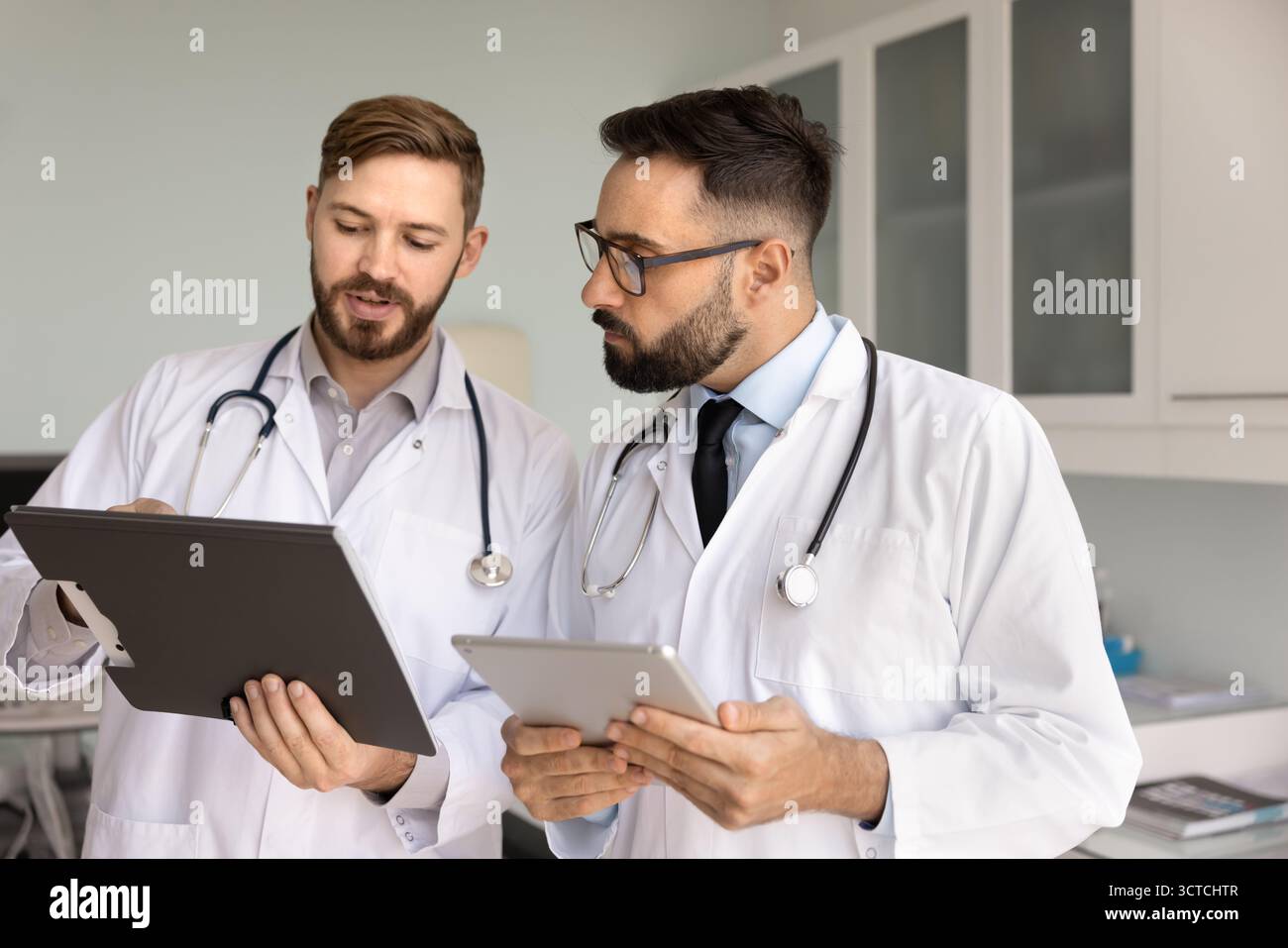 Two young 30s male doctors lead work-related discussion Stock Photo - Alamy