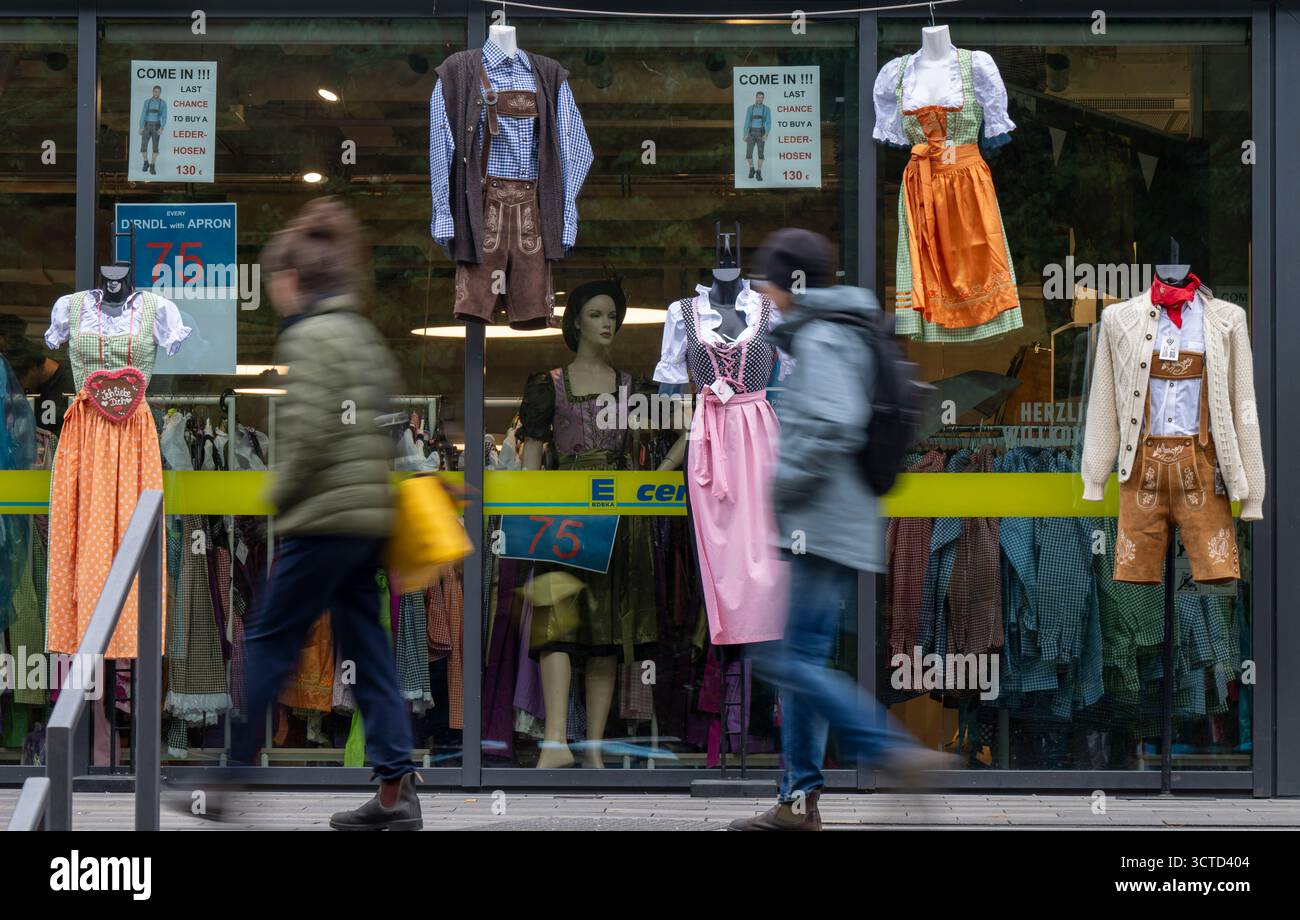 06 October 2025, Bavaria, Munich: Passers-by walk past a store selling ...