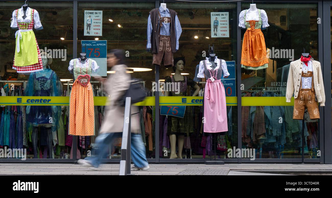 06 October 2025, Bavaria, Munich: Passers-by walk past a store selling ...