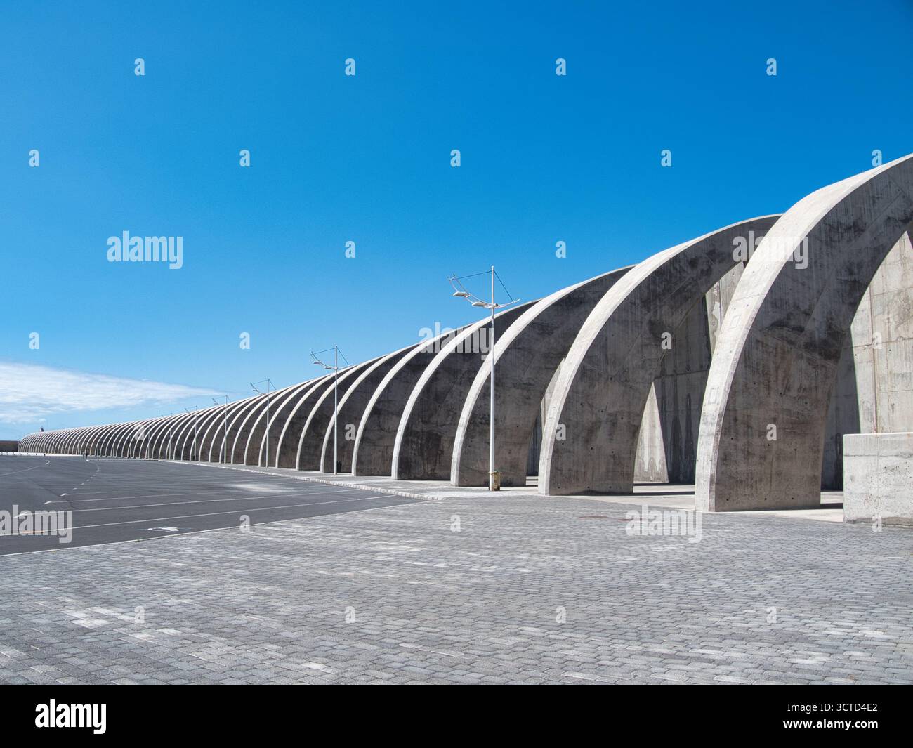 Long perspective view of a row of modern concrete arches under blue sky ...