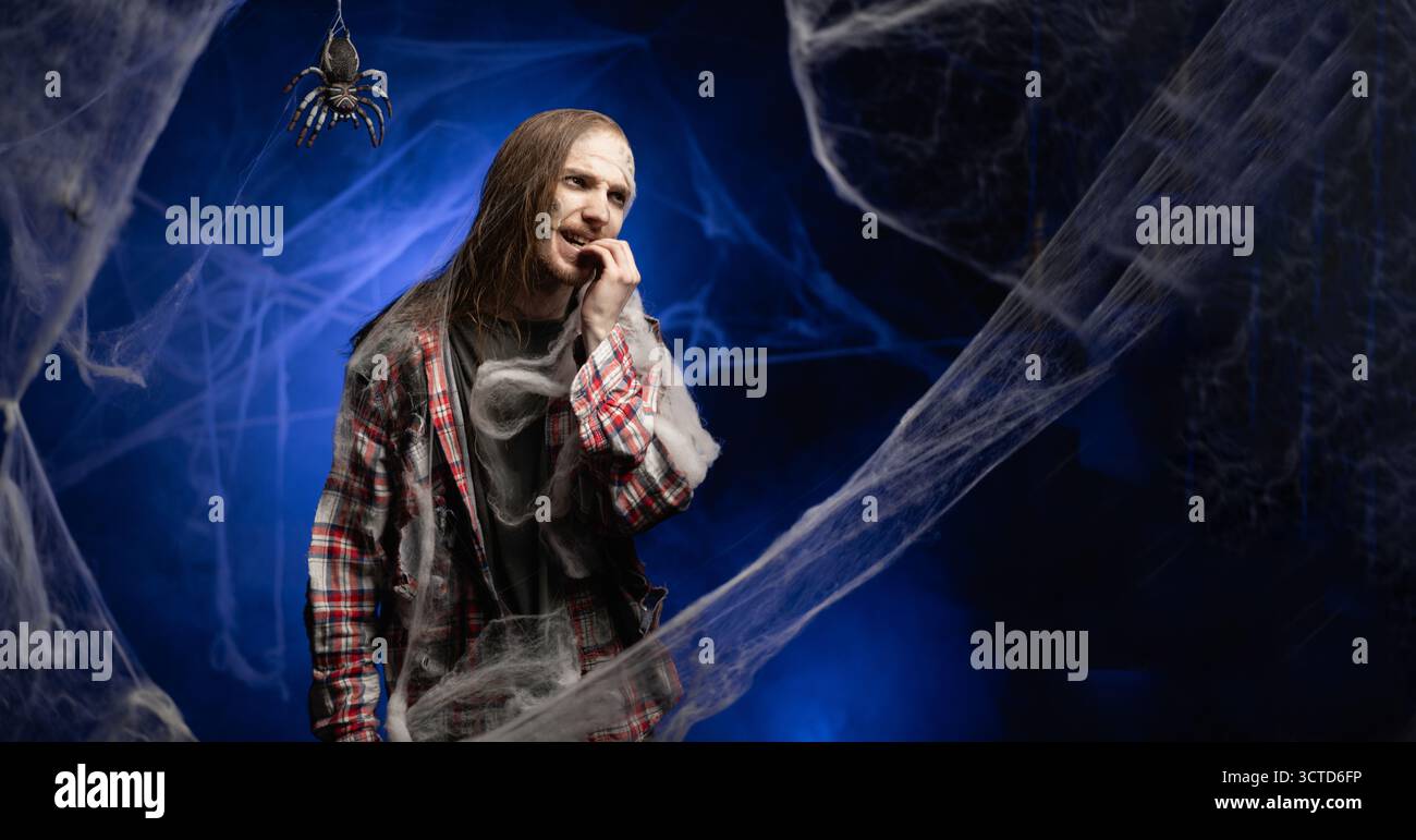 Creepy scary zombie man with ugly makeup nervous biting his nails in ...