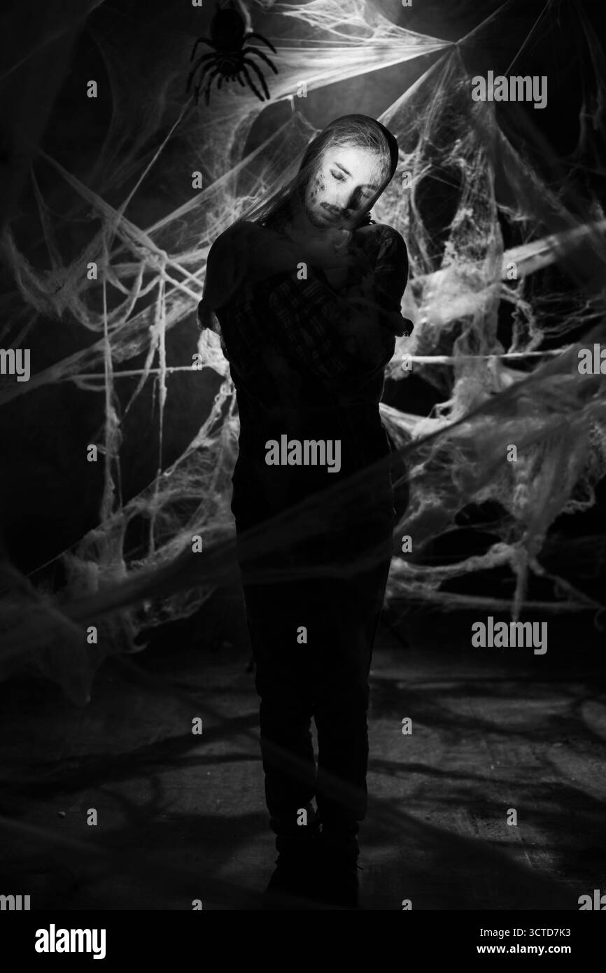 art portrait of a young man with ugly makeup wrapped with cobwebs ...