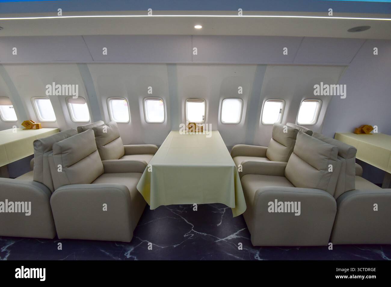 A table with a cream tablecloth and surrounding seats is shown inside ...