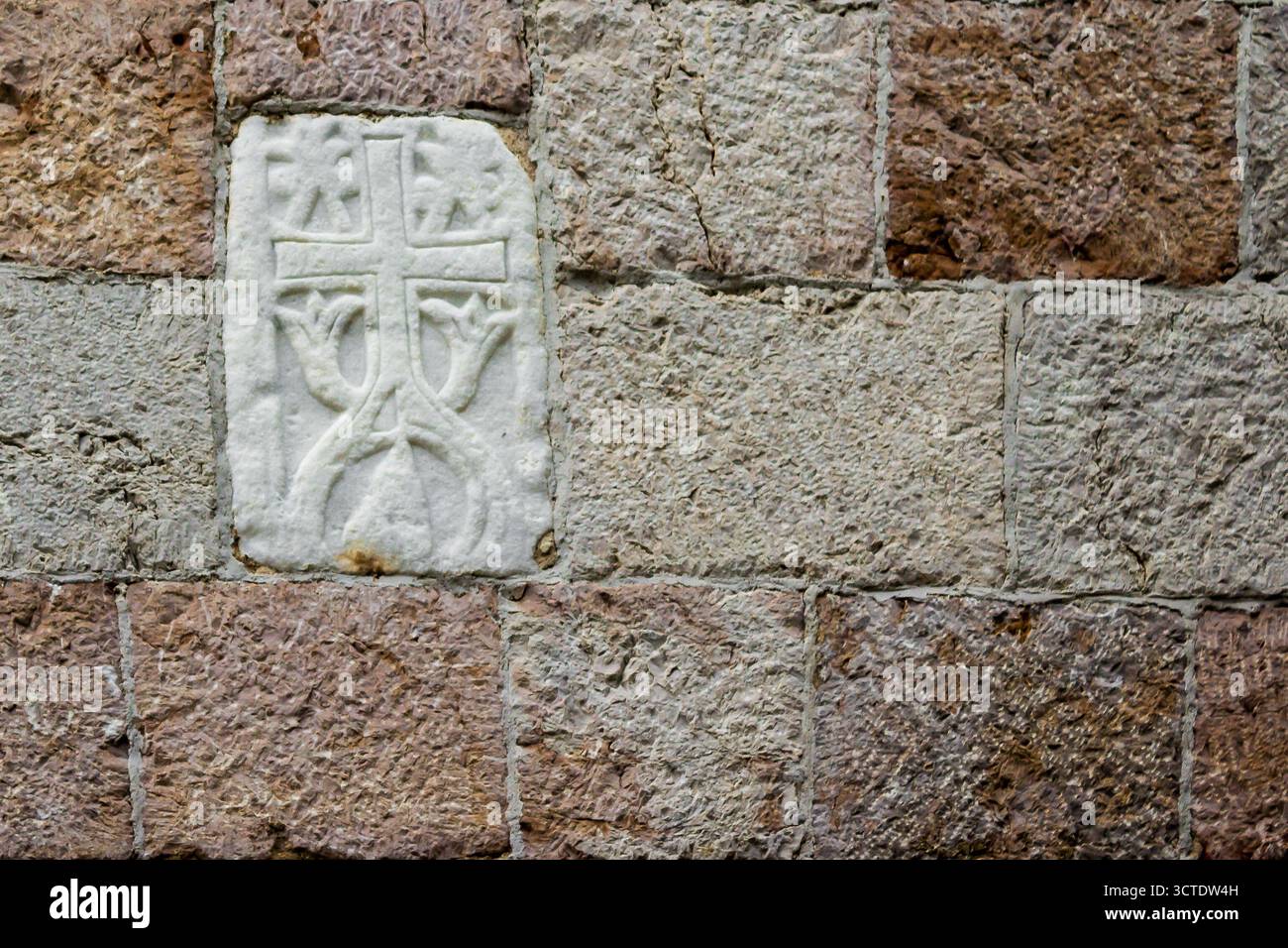 Historic stone bas-relief with a carved Christian cross on the medieval ...