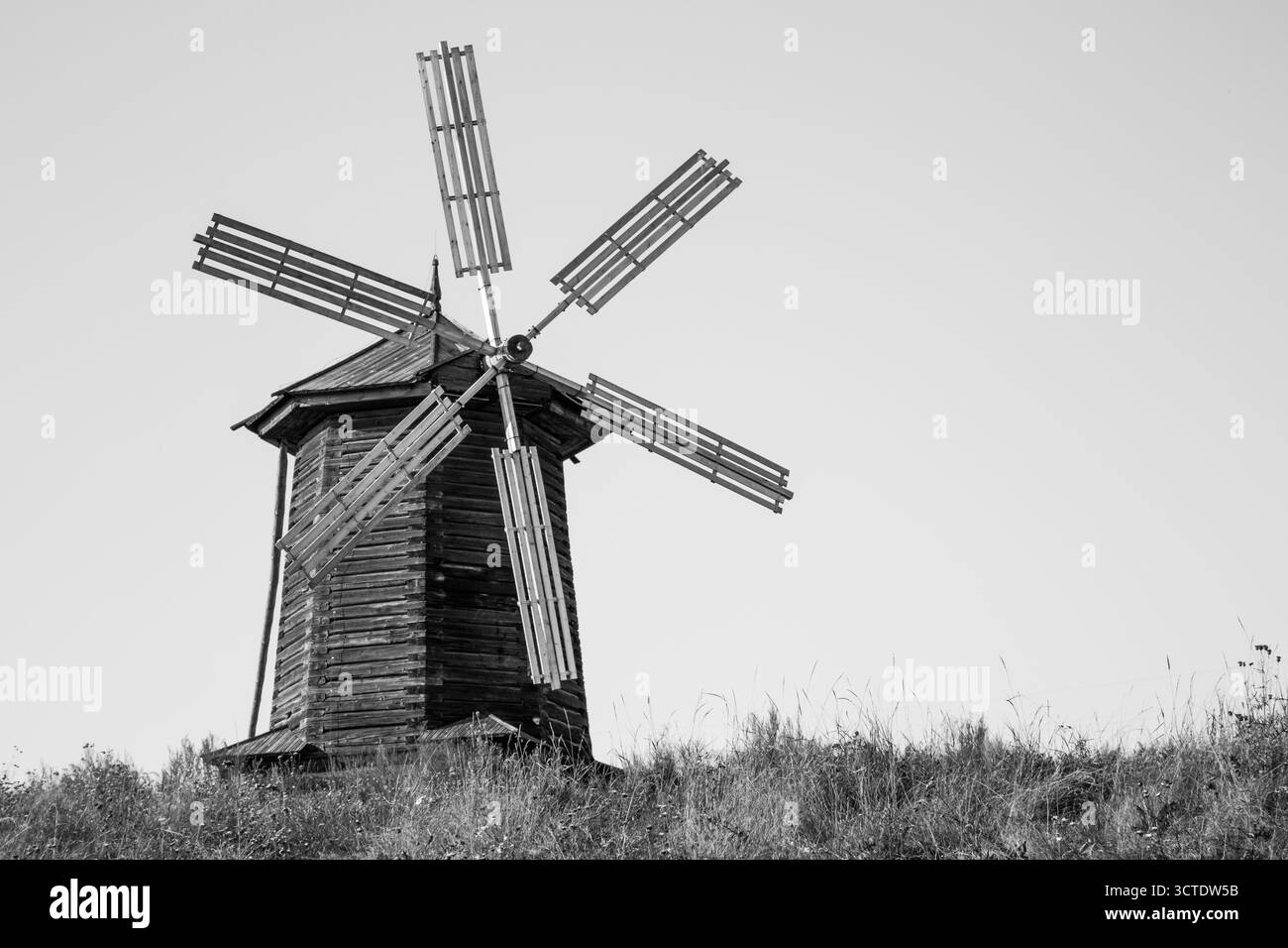 Black and white image of an old wooden windmill standing on a hill in a ...