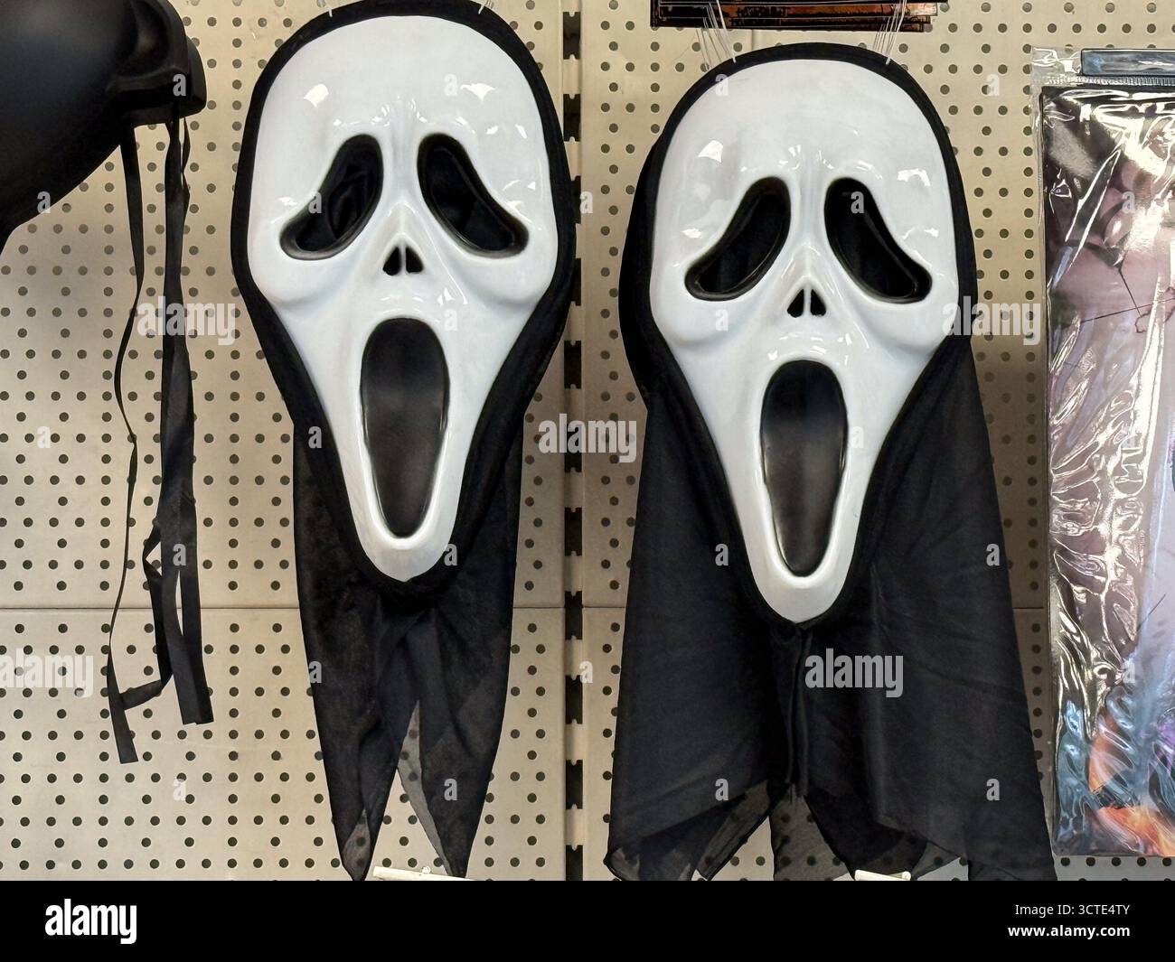 White plastic masks with wide open mouths and black drapes hanging on ...