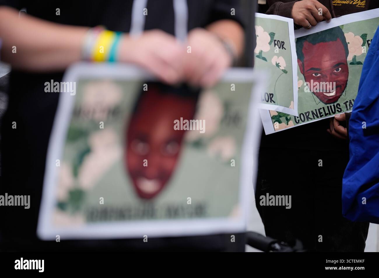 People gather with signs for a rally for Cornelius Taylor at the ...