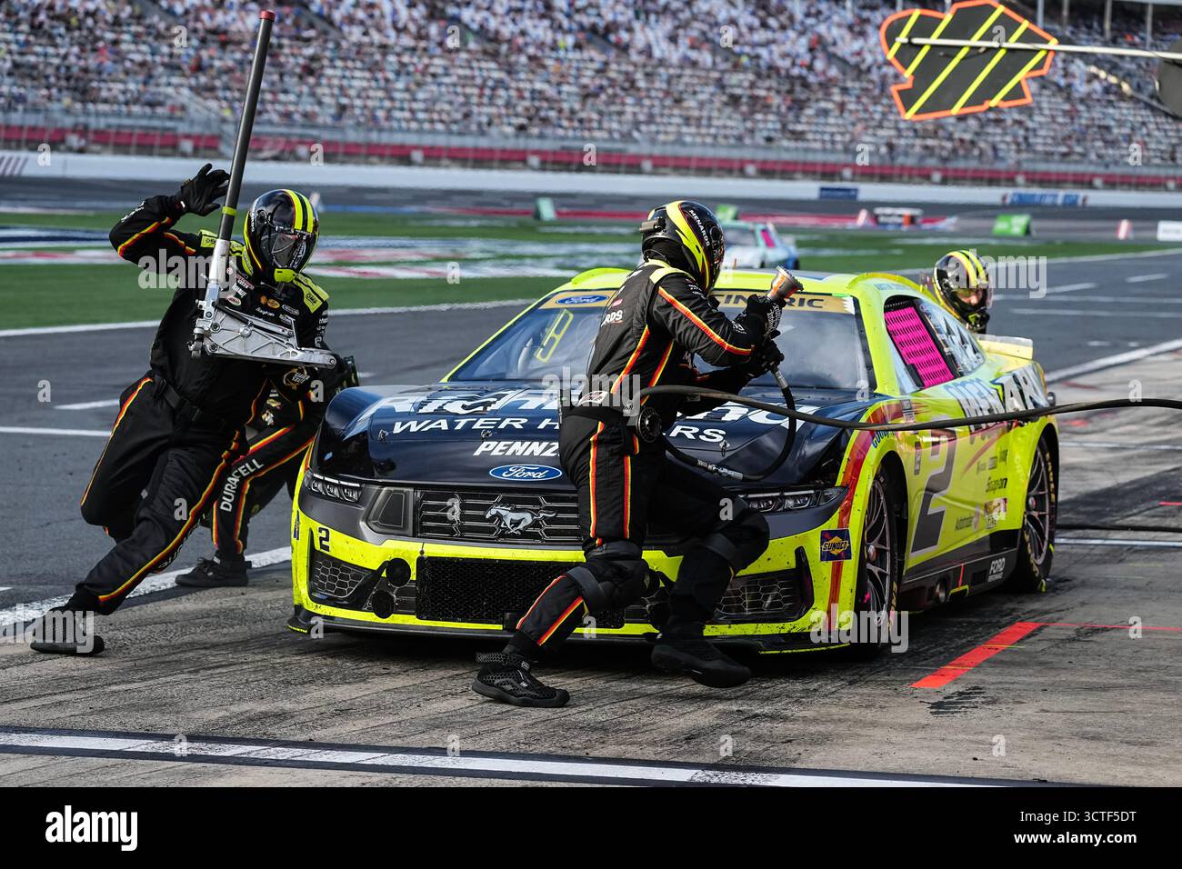 The pit crew for Austin Cindric (2) rushes to complete a pit stop ...