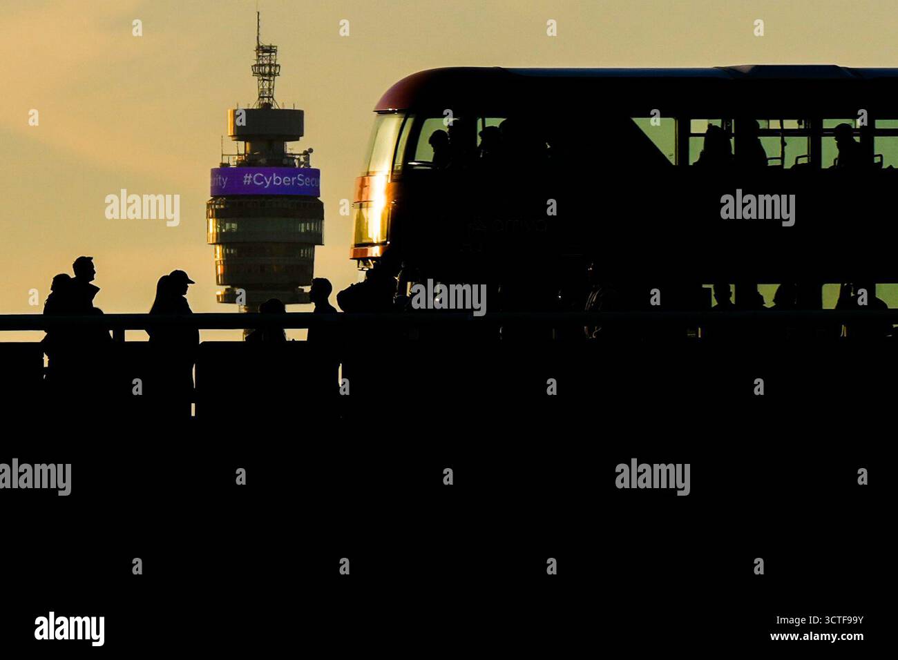 People walk and a red double-decker bus drives on the London Bridge ...