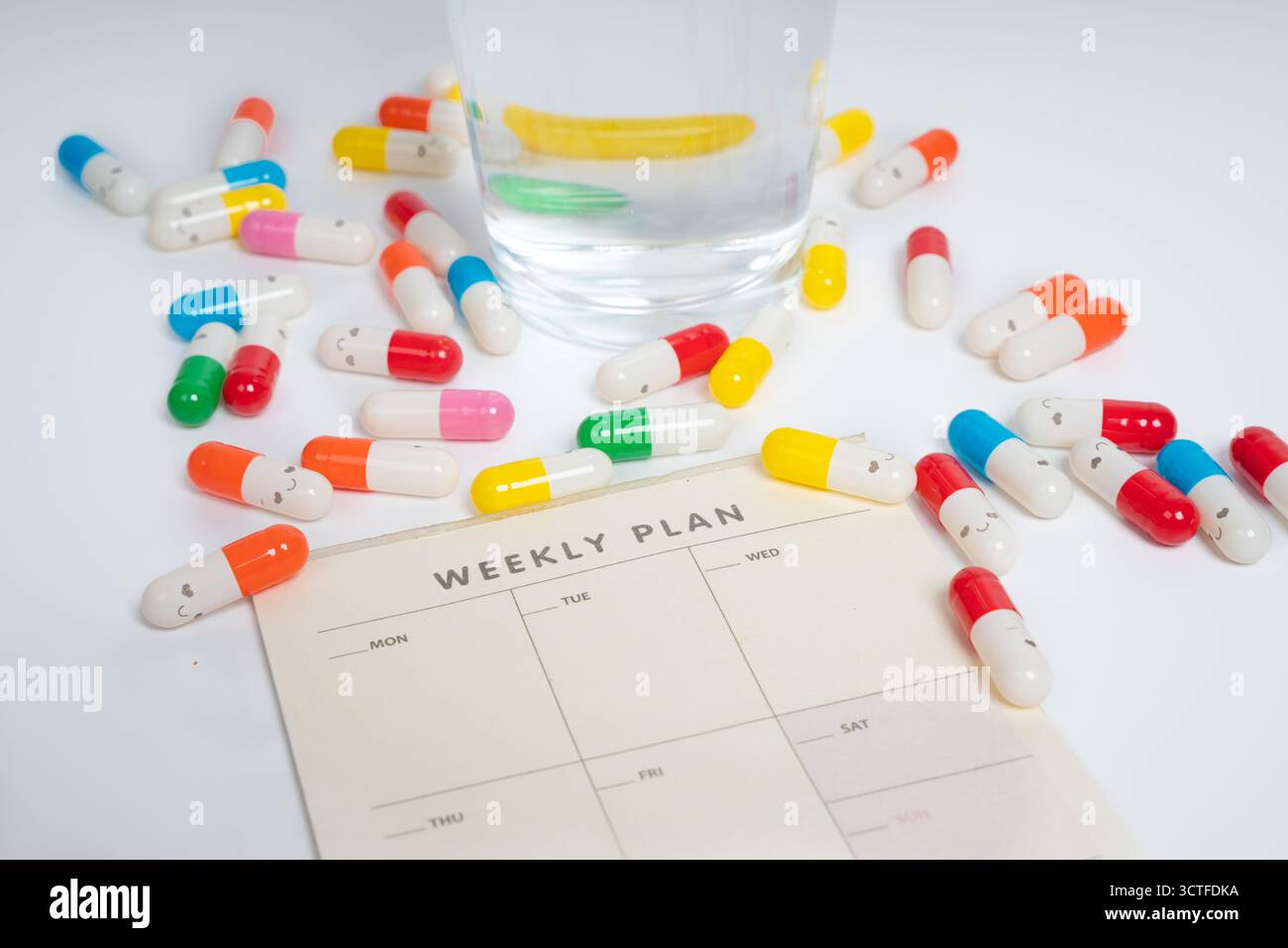 Colorful pills and water glass on weekly plan schedule sheet isolated ...