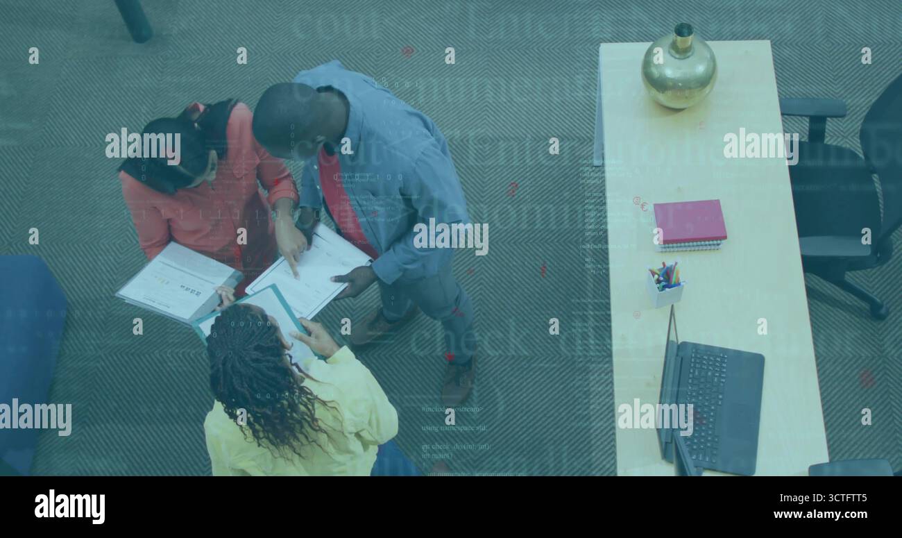 Three coworkers reviewing reports and binder in business attire in ...