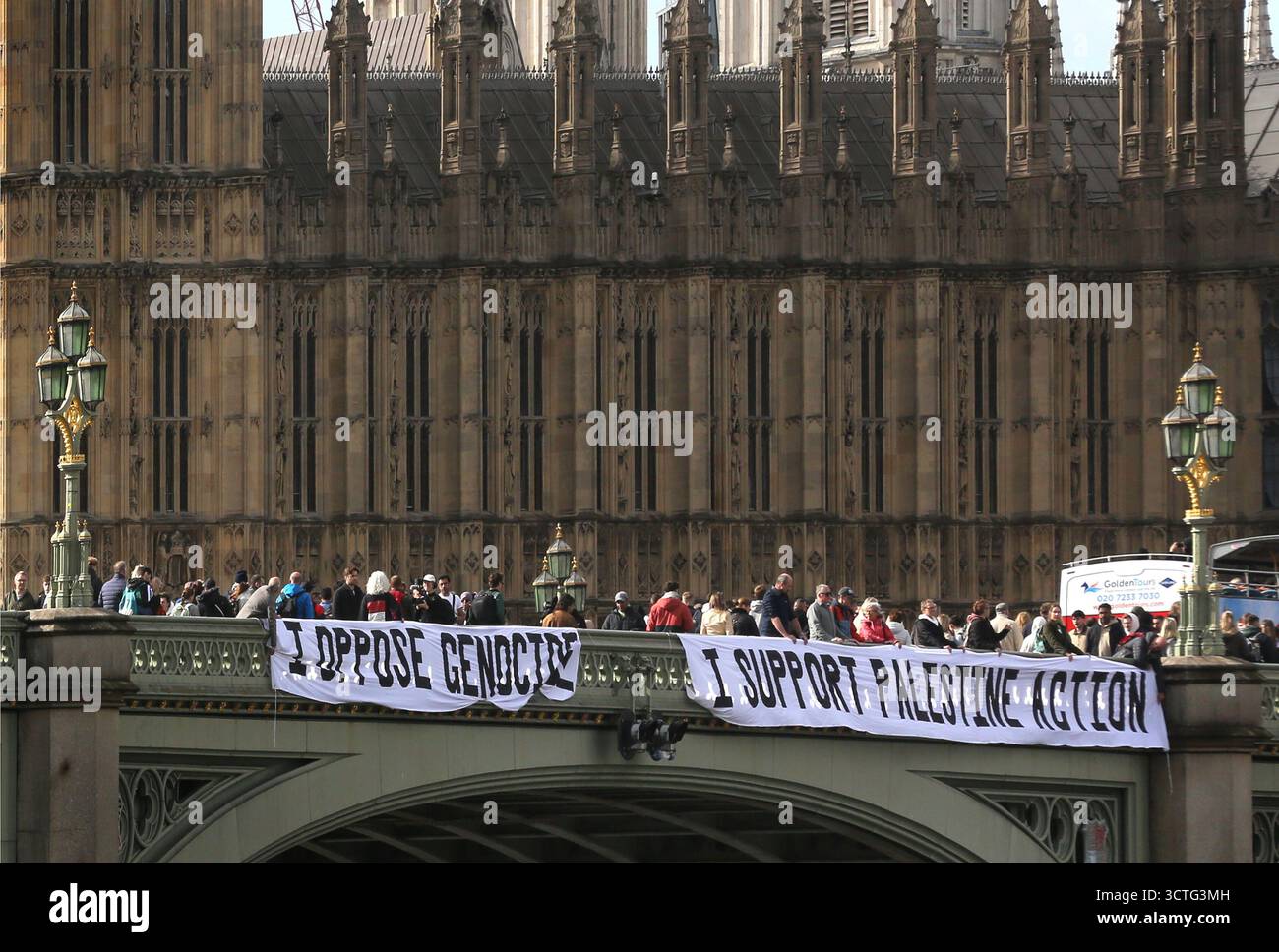 Activists hold two banners over the side of Westminster Bridge saying ...