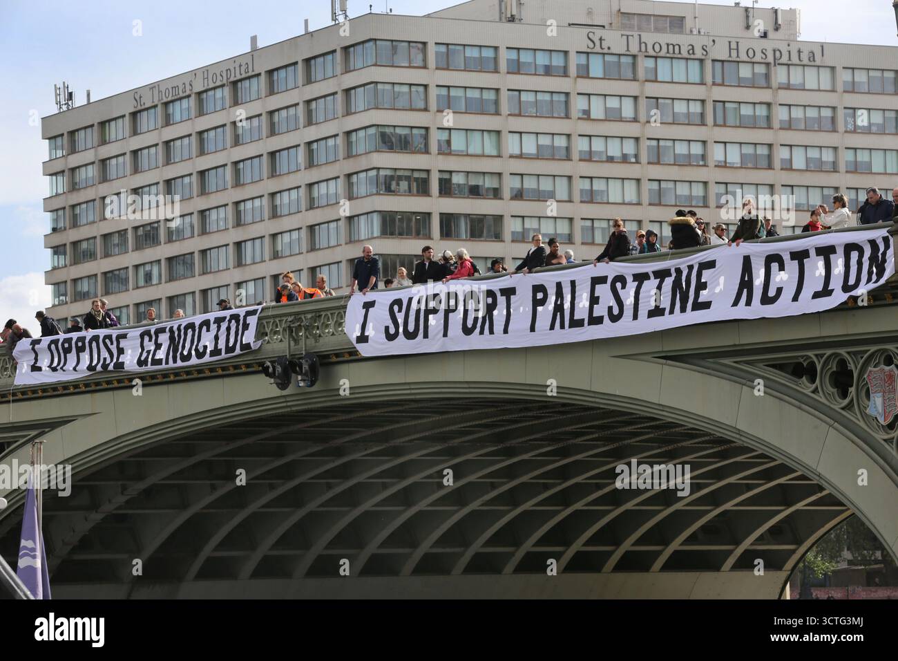 Activists hold two banners over the side of Westminster Bridge saying ...