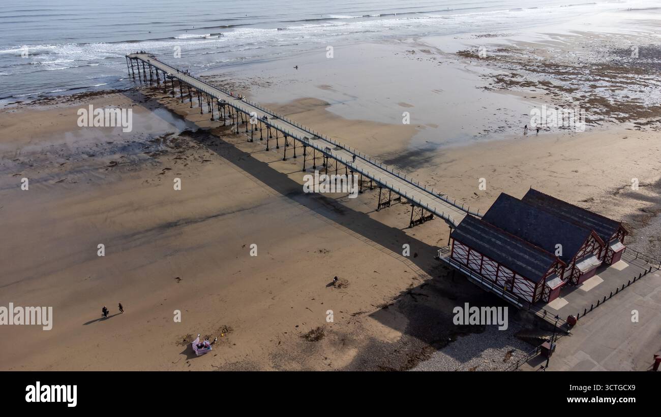 Aerial view of Saltburn Pier extending over the sandy beach and calm ...