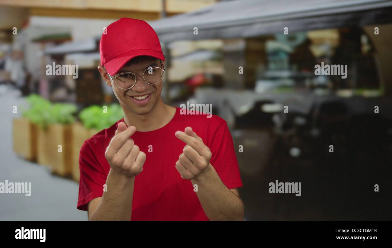 Smiling delivery man gestures finger hearts with both fingers on busy ...