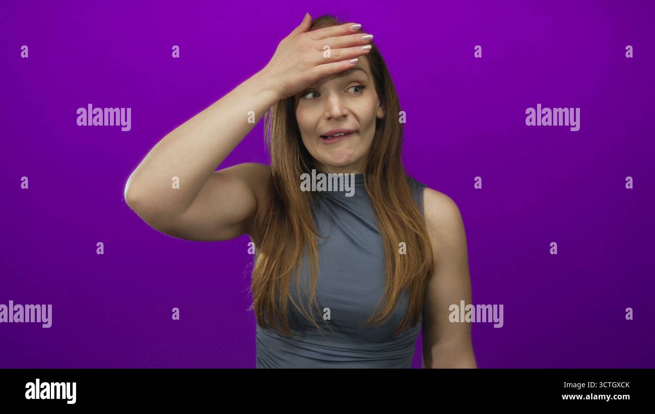 Young woman with hand on forehead and wide eyed expression in a studio ...
