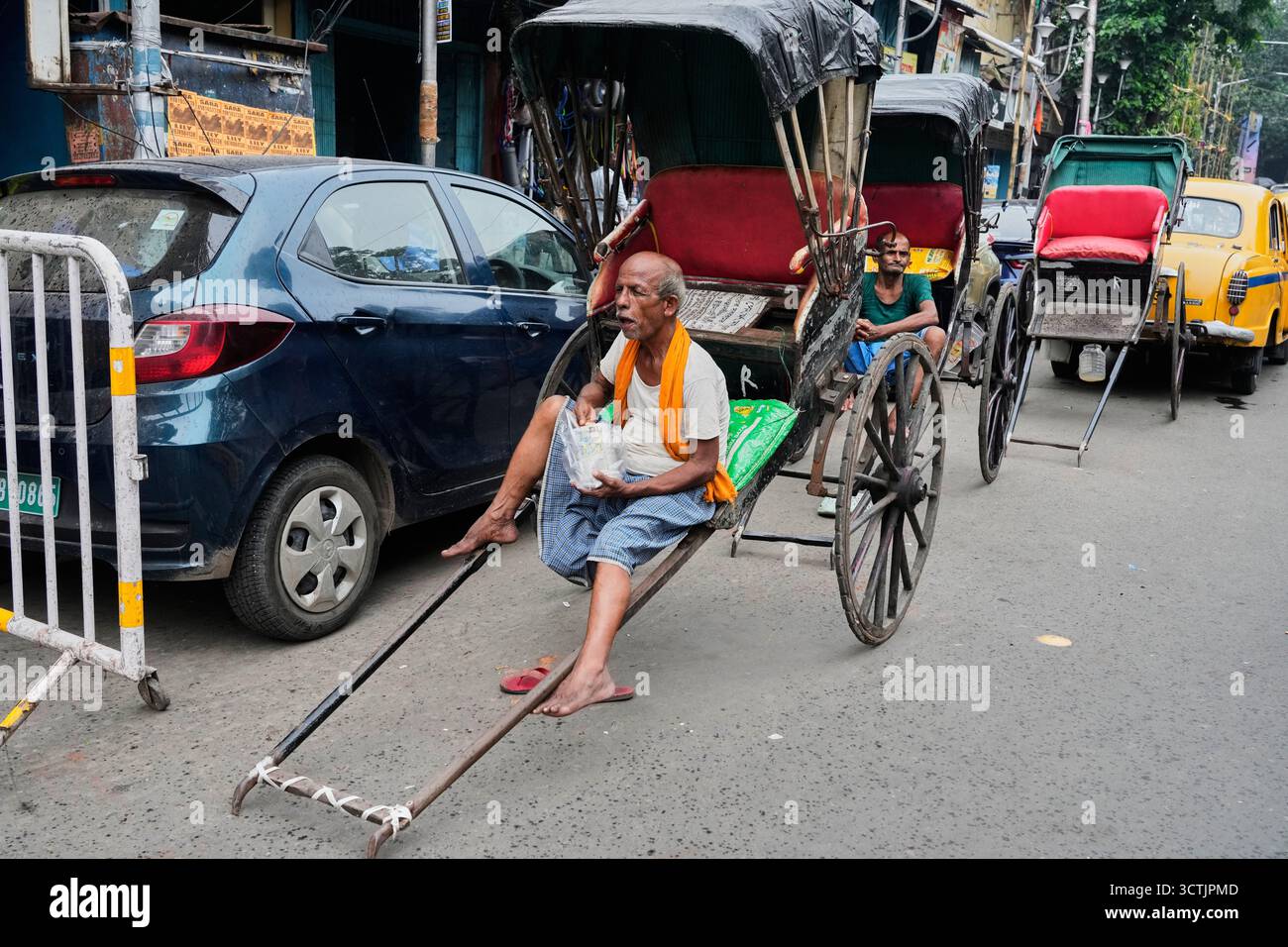 Hand rickshaw pullers park their cart beside a street as they wait for ...