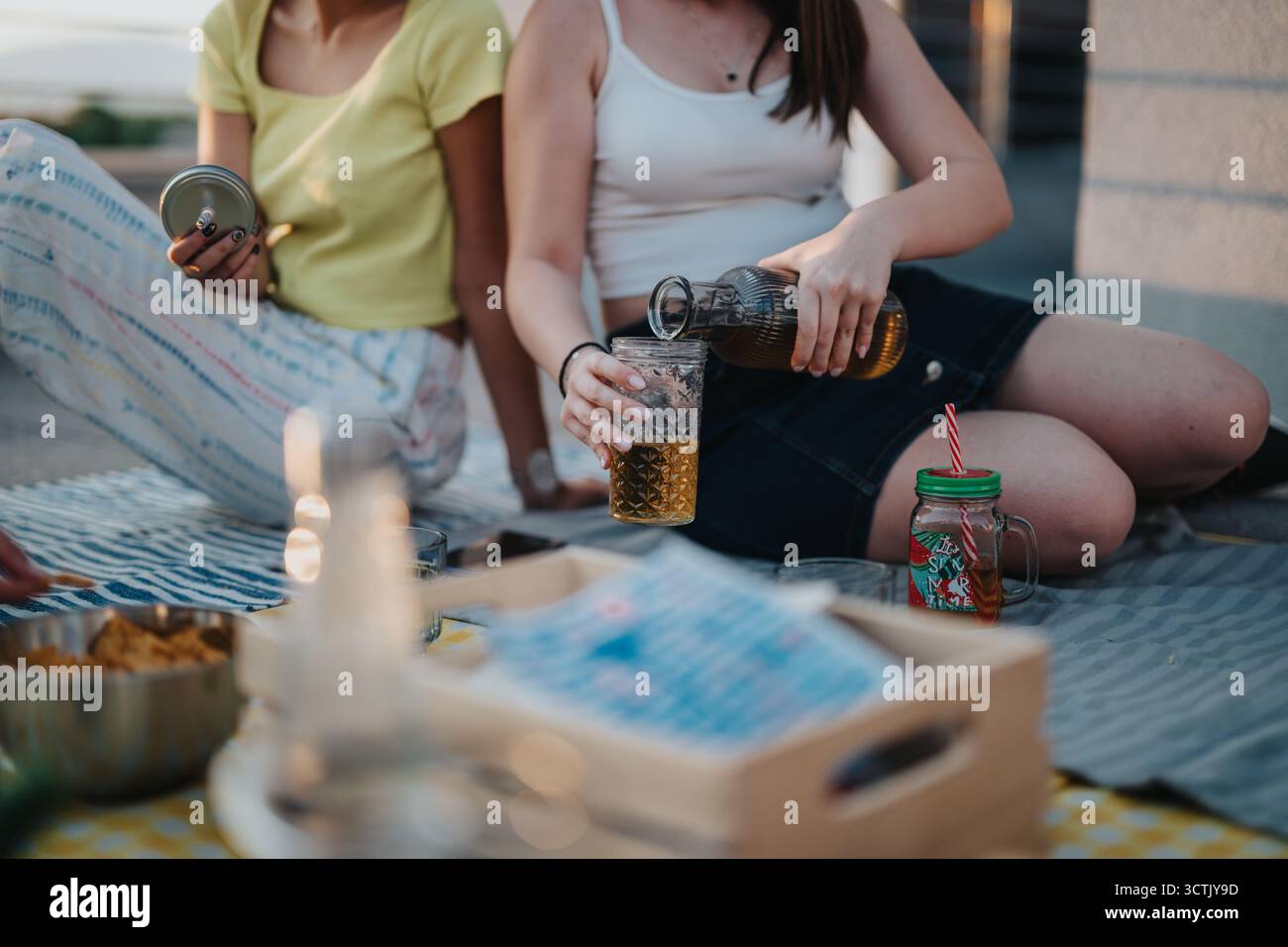 Two women enjoying a rooftop picnic with snacks and drinks Stock Photo ...