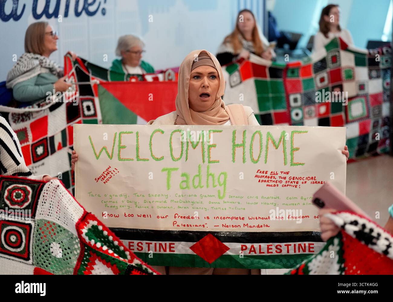 A woman holds a sign welcoming home Tadhg Hickey, one of the Irish ...