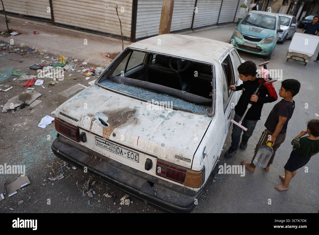 Children look at a damaged car in the Saif al-Dawla district of Aleppo ...
