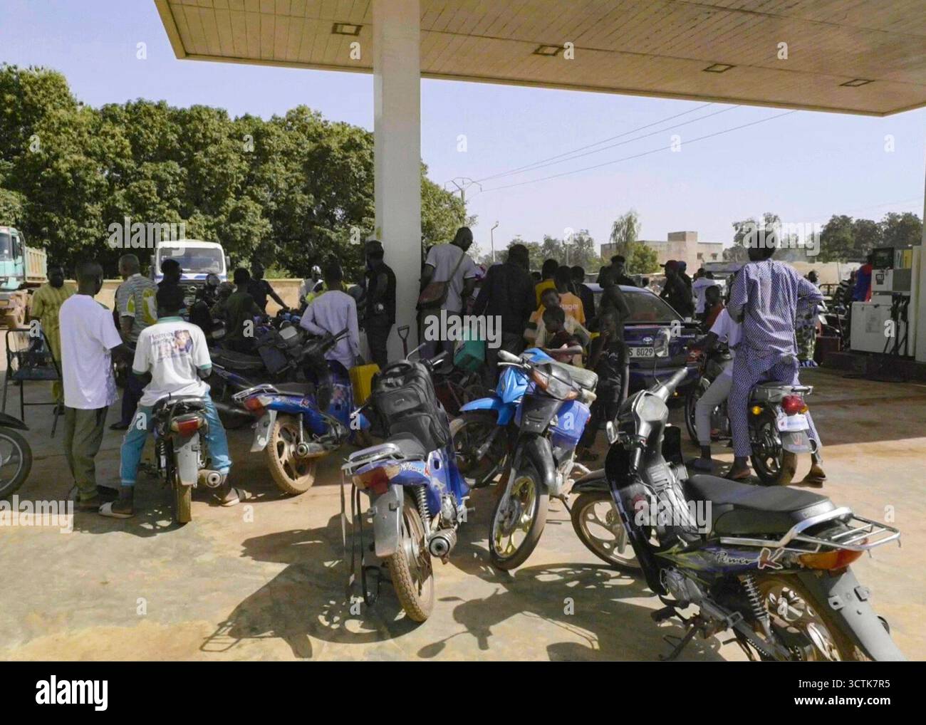 People queue with their motorcycles at a gas station amid a fuel ...