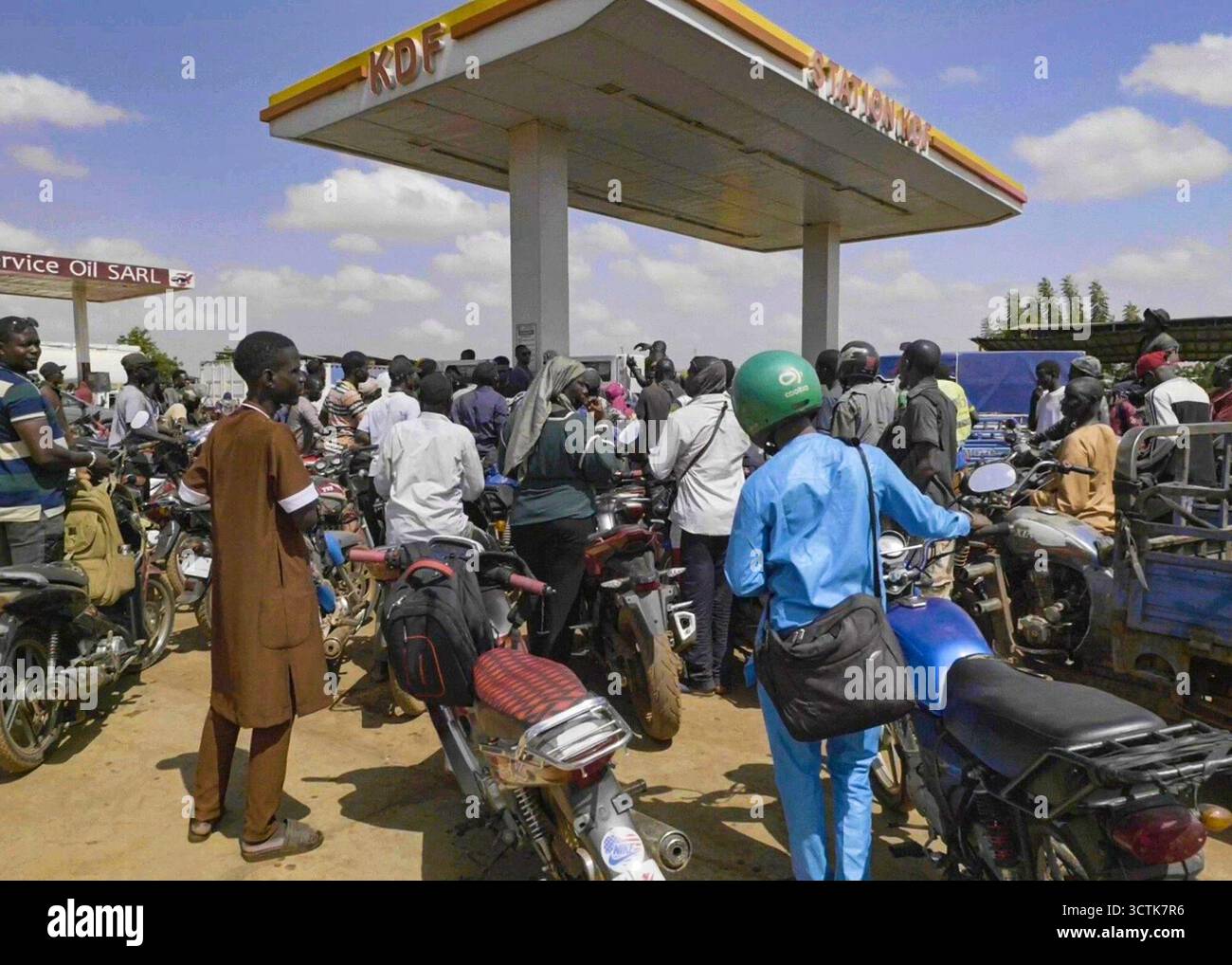 People queue with their motorcycles at a gas station amid a fuel ...